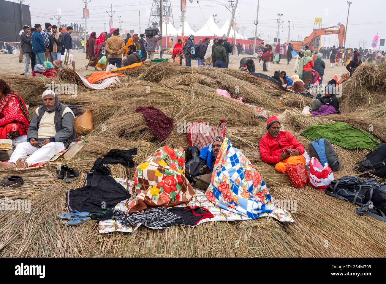 Hindu devotees rest on a pile of hay after bathing at the confluence of ...
