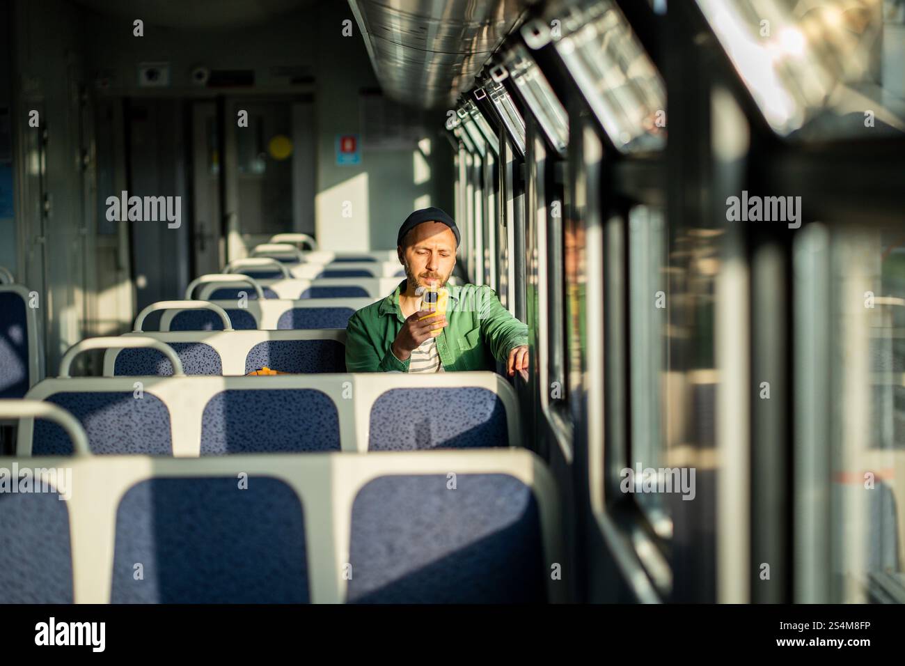 Focused man traveling to work on train with smartphone scrolling social ...