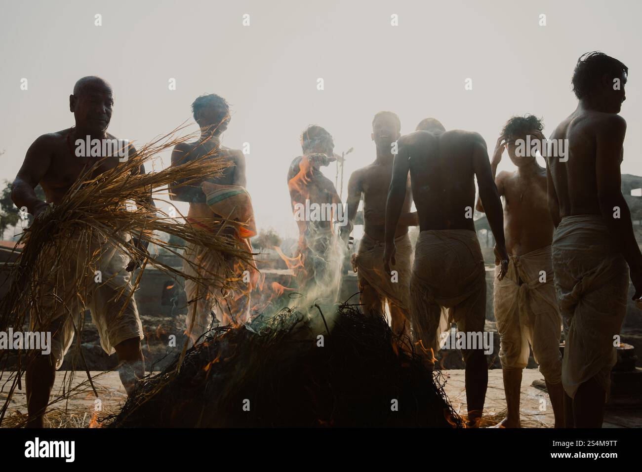 Devotees warm themselves near a fire after performing a religious ...