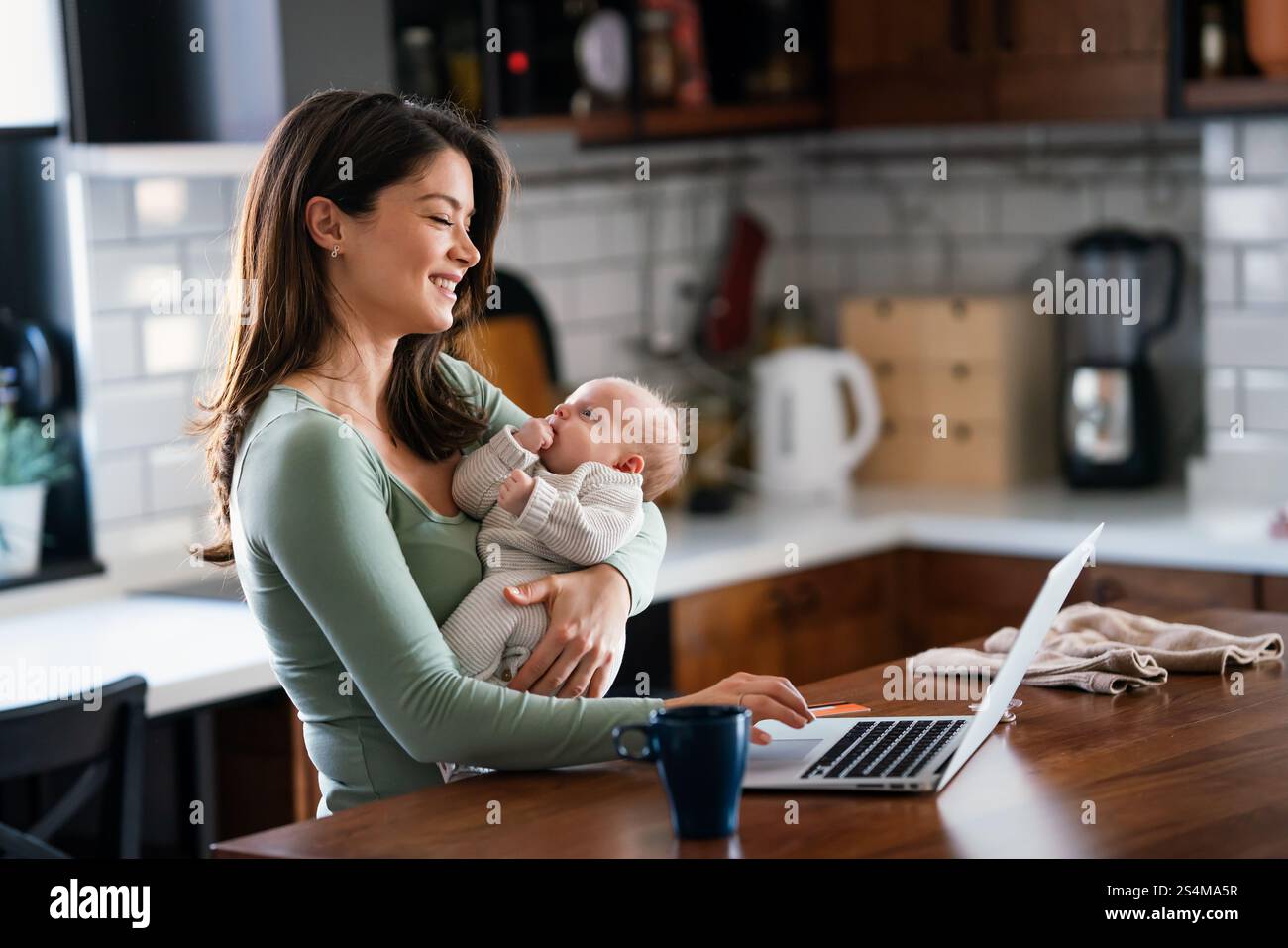 Stay at home mom working remotely on laptop while taking care of her ...