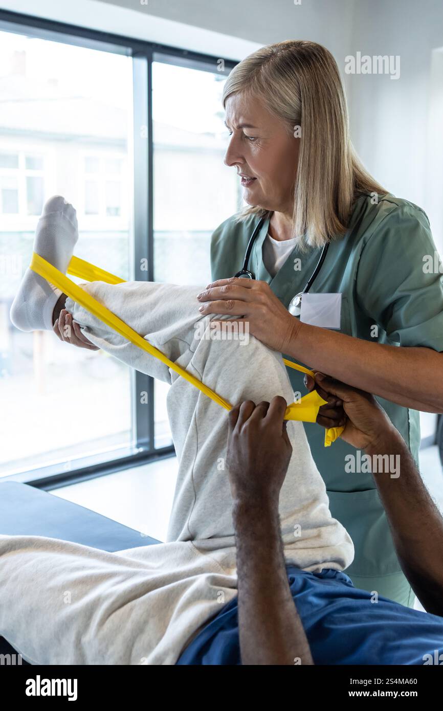 Female doctor helping a male patient during exercising with stretch ...