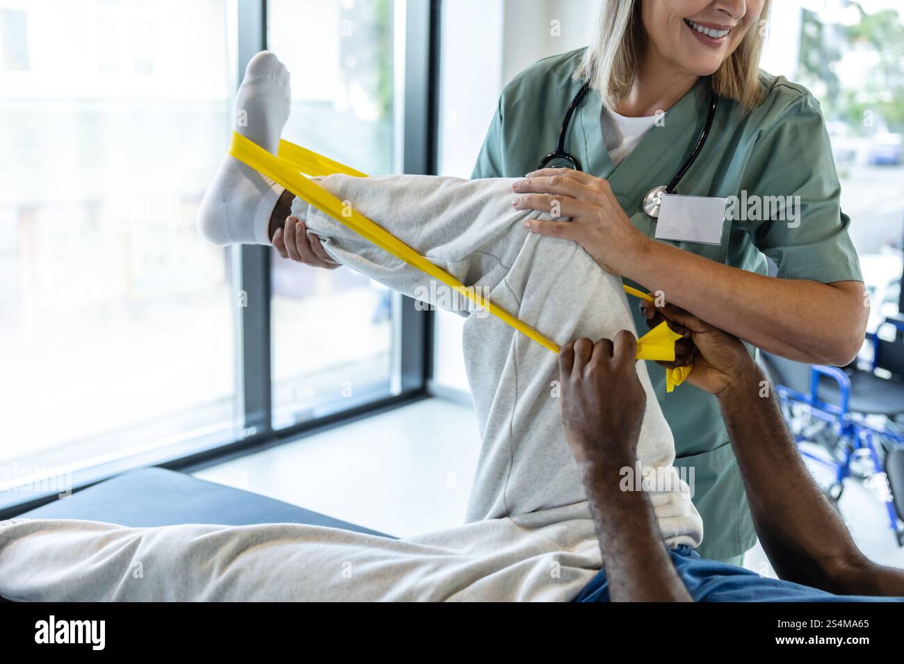 Female doctor helping a male patient during exercising with stretch ...
