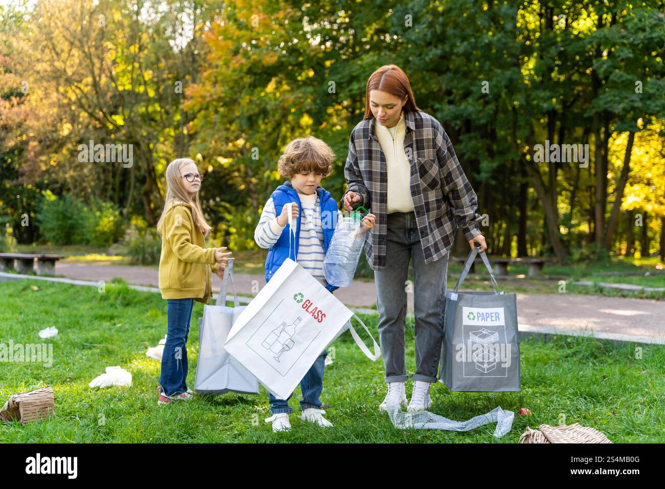 Kids with teacher collecting garbage in park working in volunteers ...