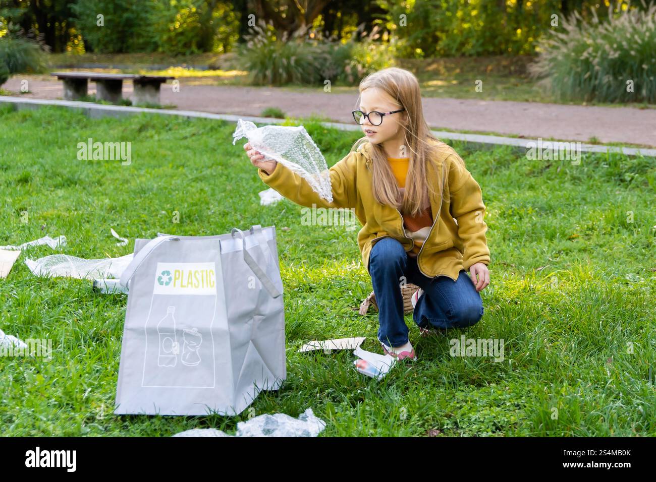 Little girl picking up trash outdoors sorting plastic waste into ...