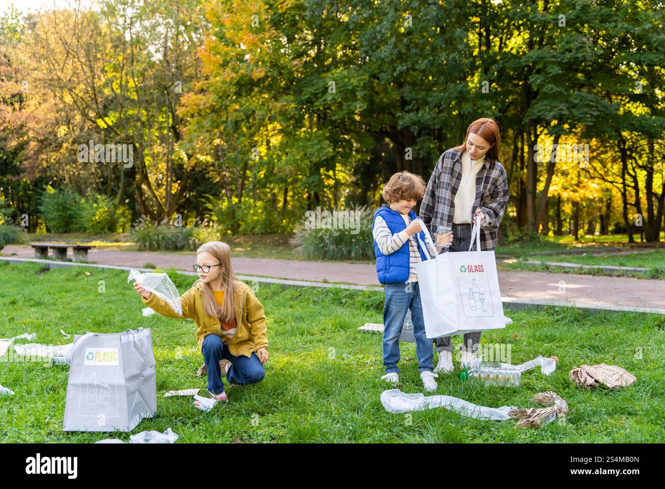 Children picking up trash outdoors with teacher sorting plastic waste ...