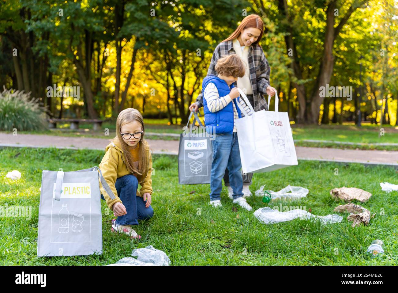 Children picking up trash outdoors with teacher sorting plastic waste ...