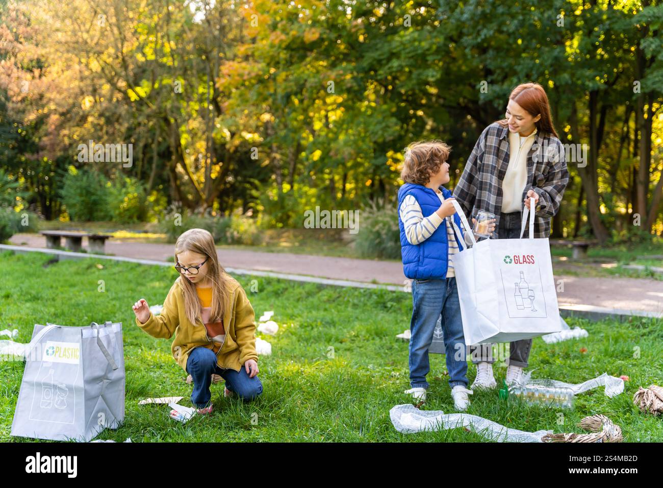 Boy and girl collecting trash in park with teacher participating in ...