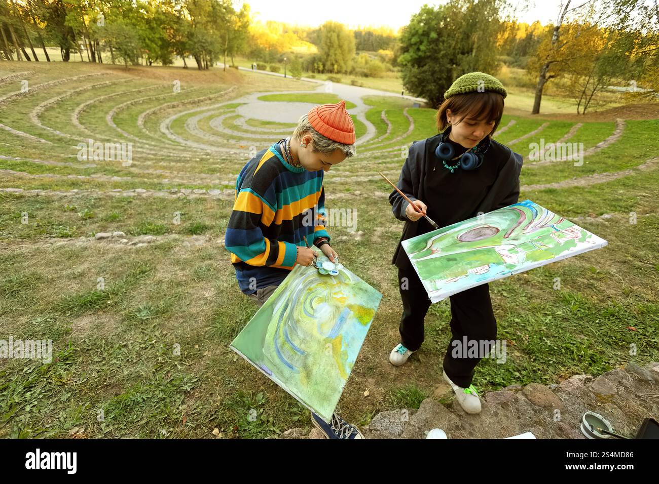 two young and innovative female artists conducting an outdoor painting ...