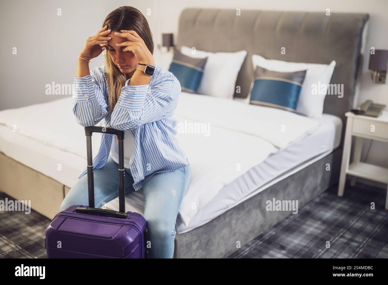 Tourist arrived in hotel room with her suitcase. She is tired of travel ...