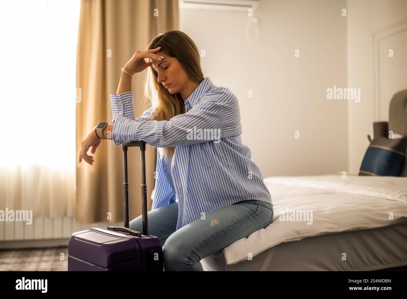 Tourist arrived in hotel room with her suitcase. She is tired of travel ...