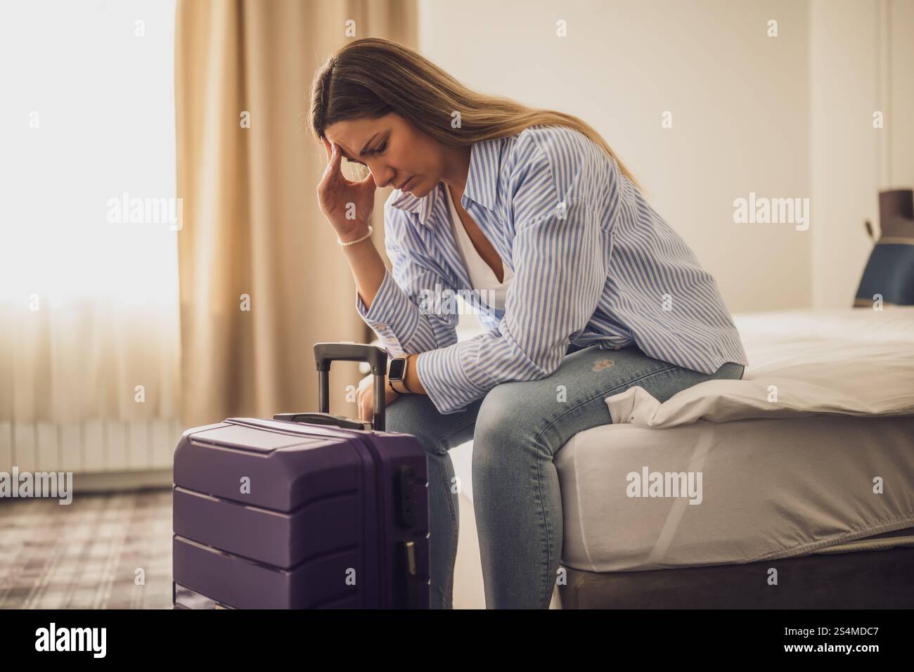 Tourist arrived in hotel room with her suitcase. She is tired of travel ...