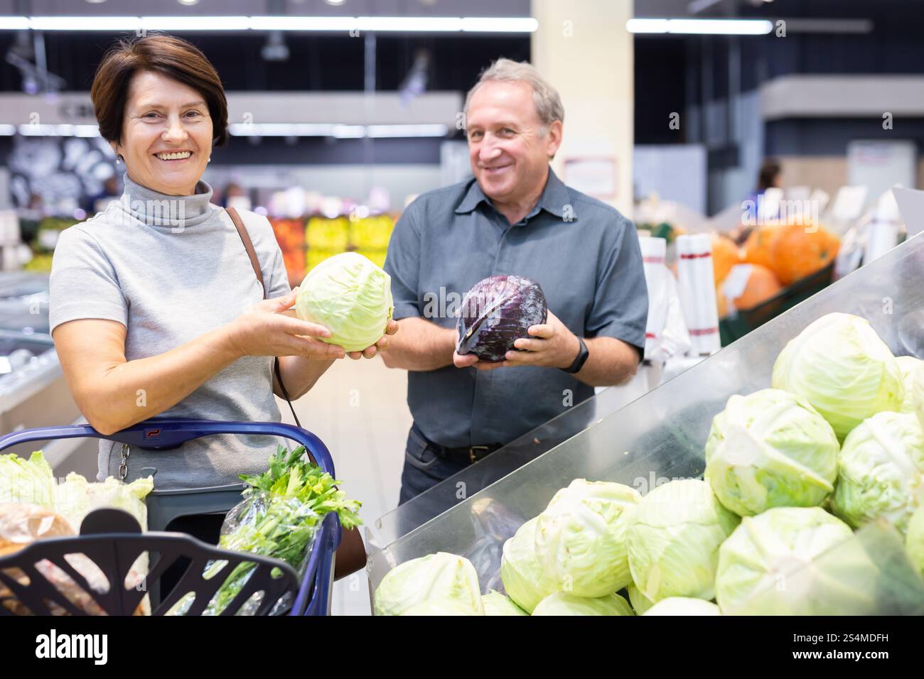 Husband and wife choose and buy fresh cabbage in grocery store Stock ...