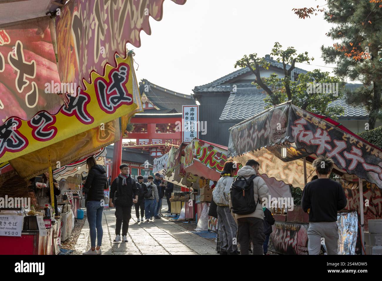 After a shrine visit, tourists check some food stands, which prepare ...