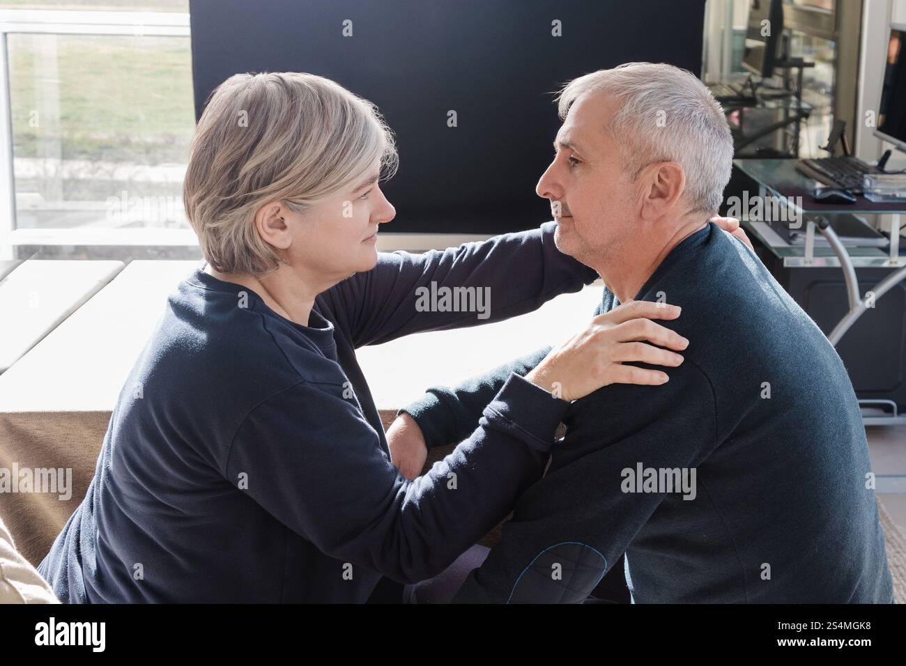 An elderly couple shares an intimate, tender moment in a cozy indoor ...