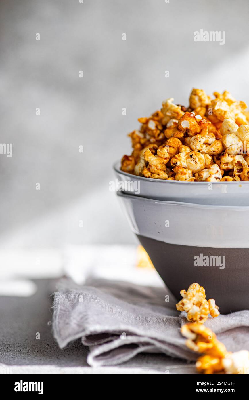 A bowl of sweet caramel popcorn on a grey napkin, background softly ...