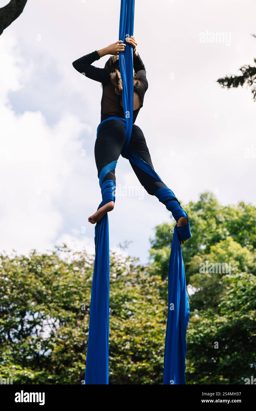 Aerial gymnast executes a mesmerizing routine on blue silks against ...