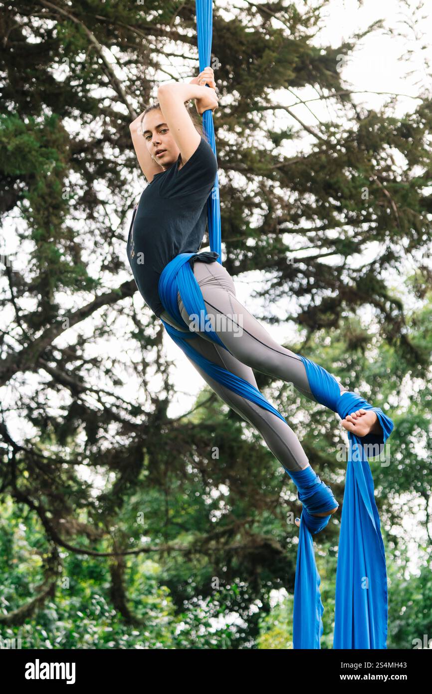 An aerialist performs acrobatics on blue fabric in a Bogota park ...
