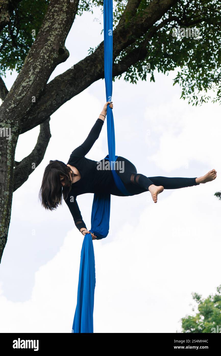 An aerialist performs stunning acrobatics on blue fabric, suspended in ...