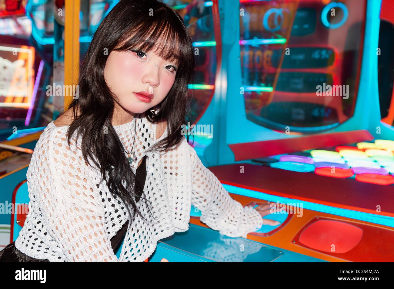 An Asian Gen Z girl enjoys an arcade game, surrounded by colorful ...