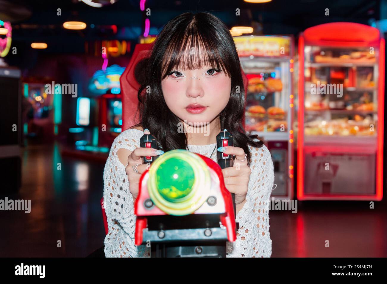Asian Gen Z girl enjoying her time in a vibrant arcade, surrounded by ...
