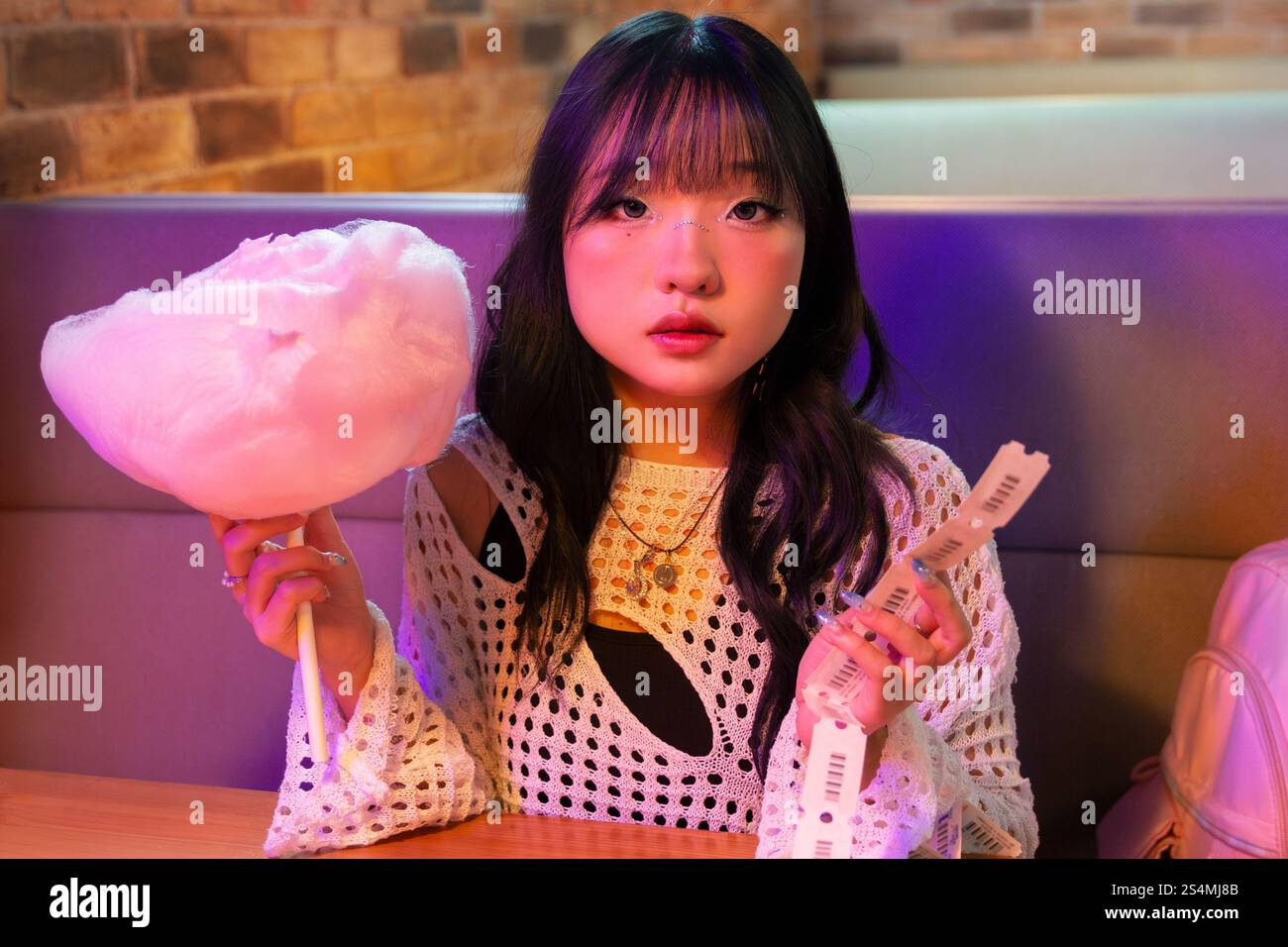 Asian Gen Z girl enjoys a fun day, holding cotton candy and tickets The ...