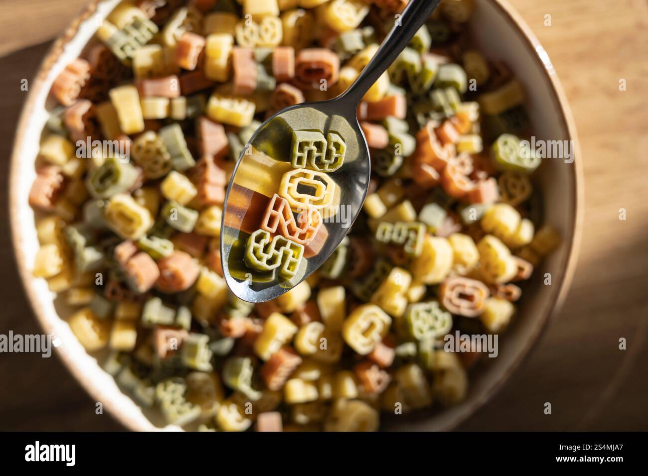 Top view of a metal spoon lifting colorful number shaped pasta from a ...