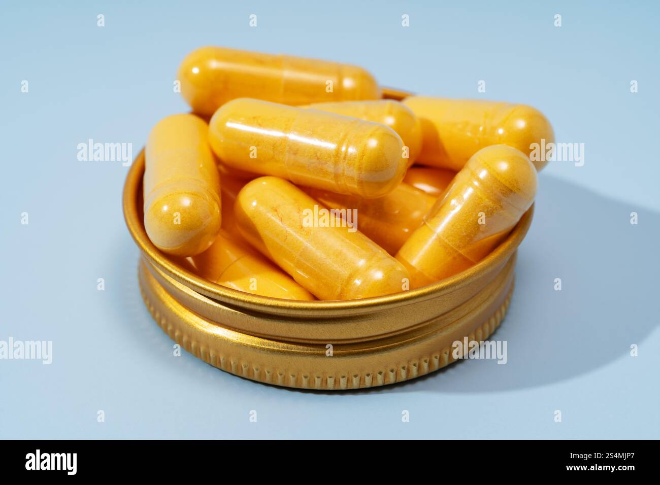 Vibrant orange capsules neatly contained in a small golden circular box ...