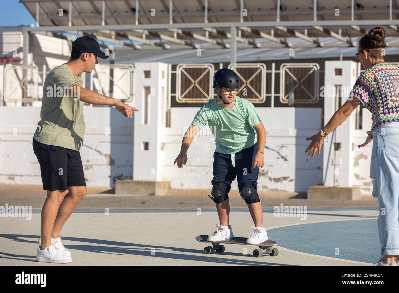Down syndrome teenager skateboarding with encouragement and support ...