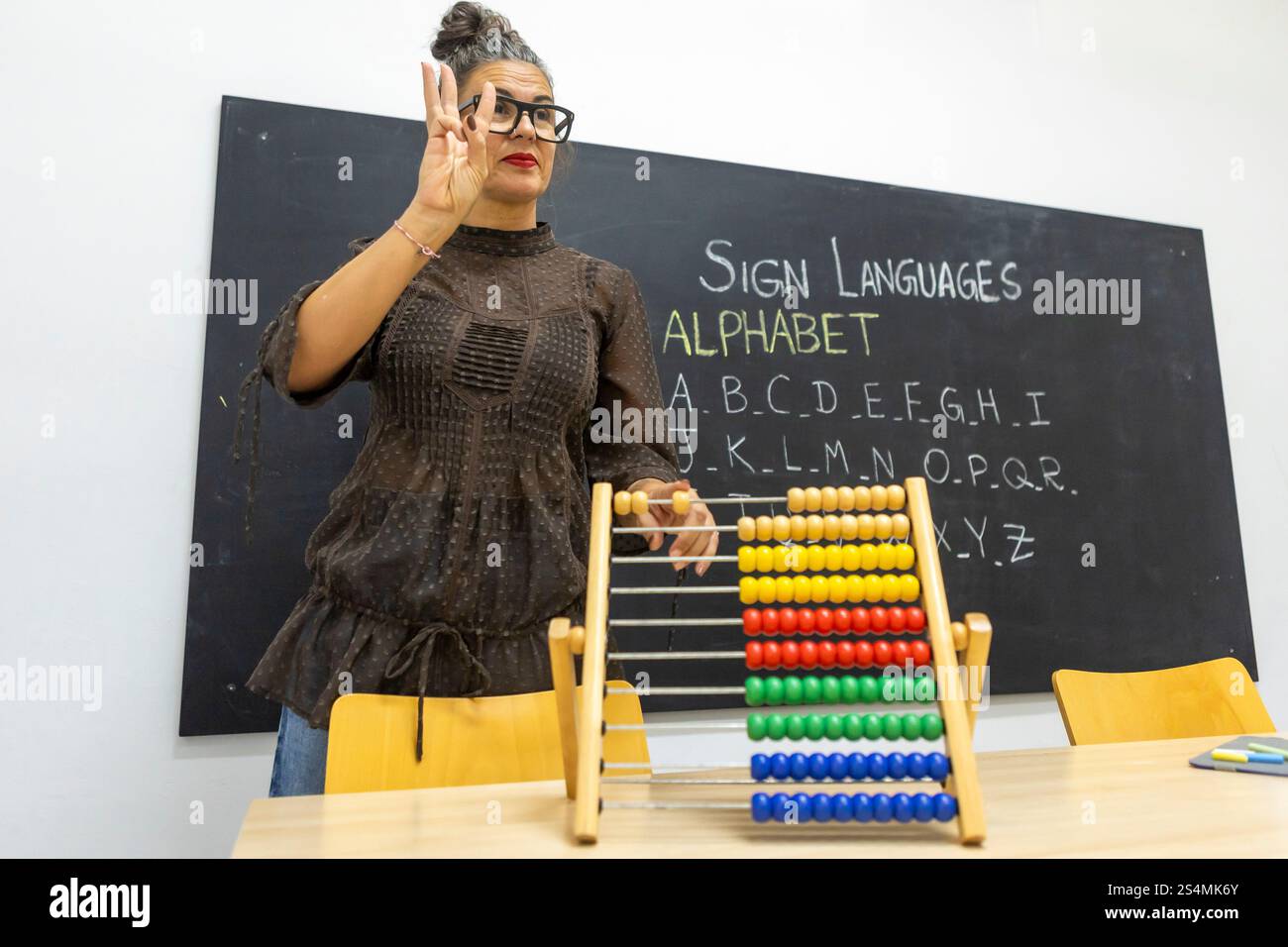 A teacher demonstrates the sign language alphabet in a classroom An ...