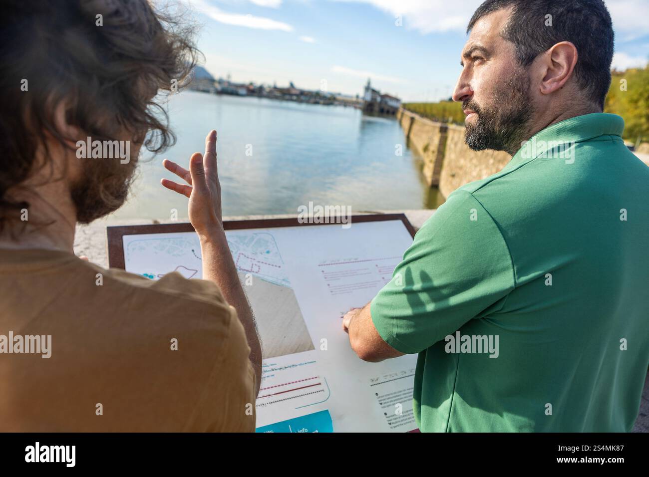 Two friends stand by a waterfront, using a tactile map for navigation ...