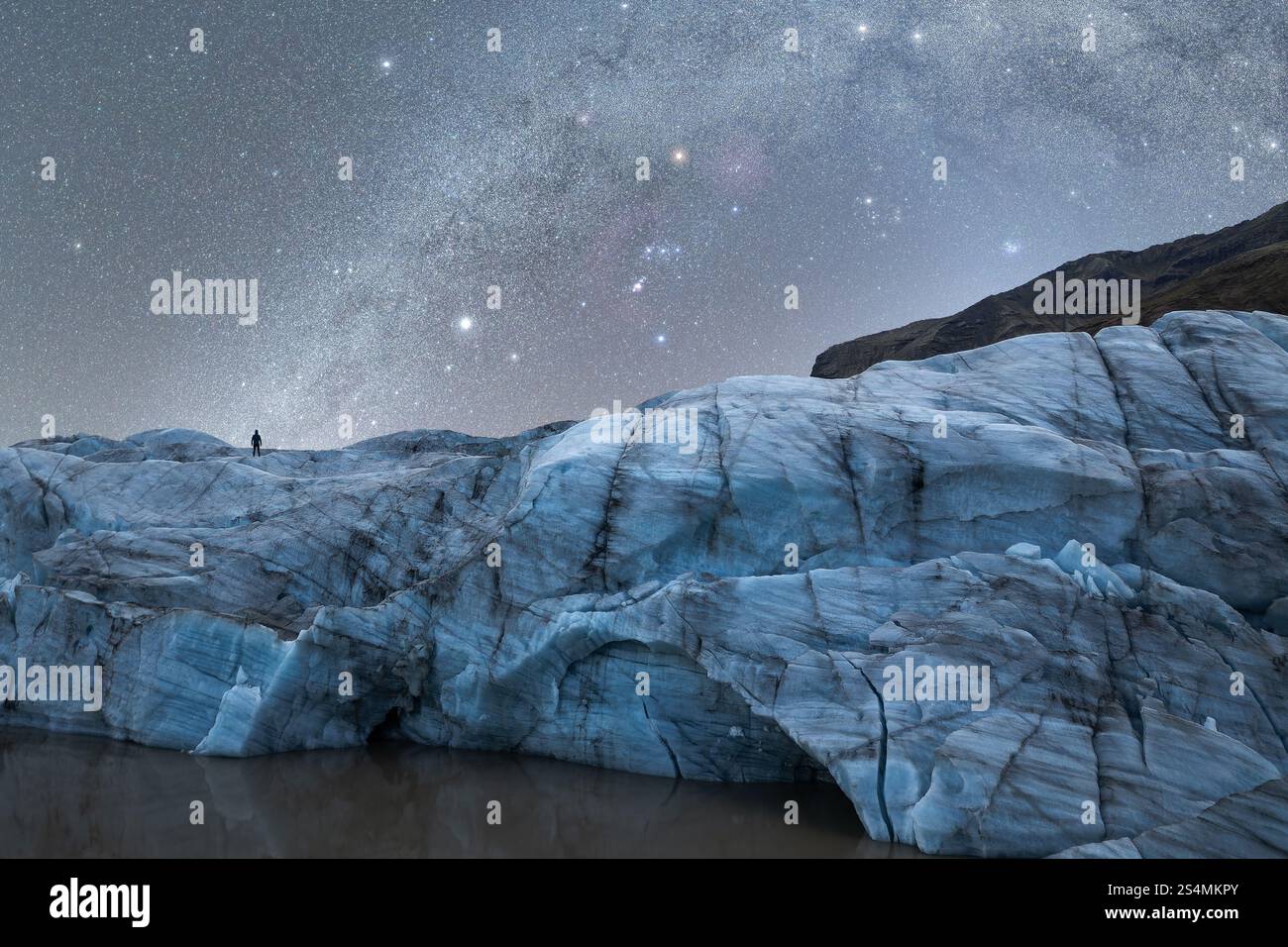 A lone figure stands atop a majestic glacier in Iceland The night sky ...