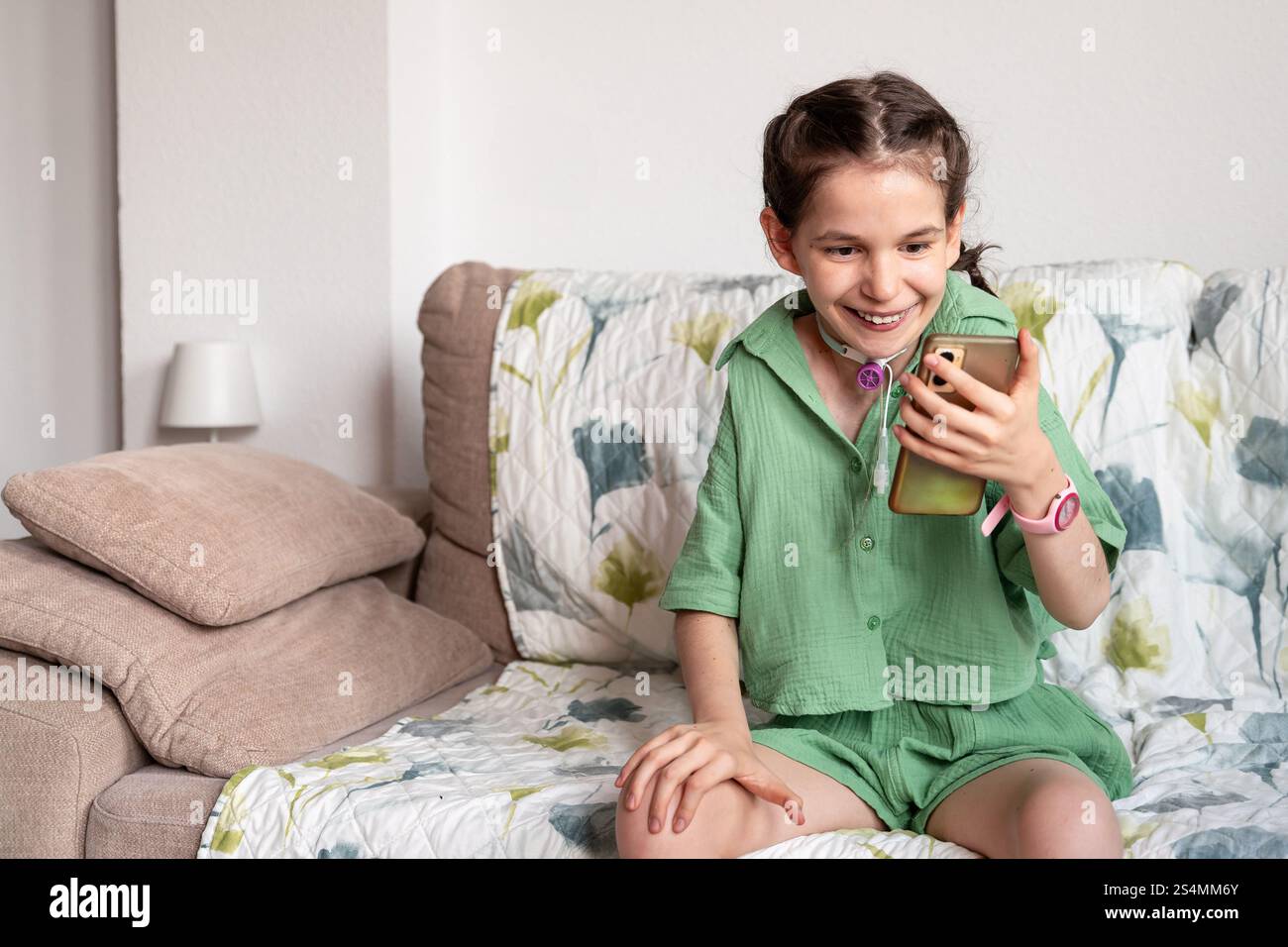 A cheerful young girl with a tracheostomy smiles as she engages with a ...