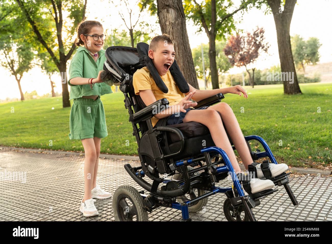 Two children with disabilities enjoy a sunny day in the park. The boy ...