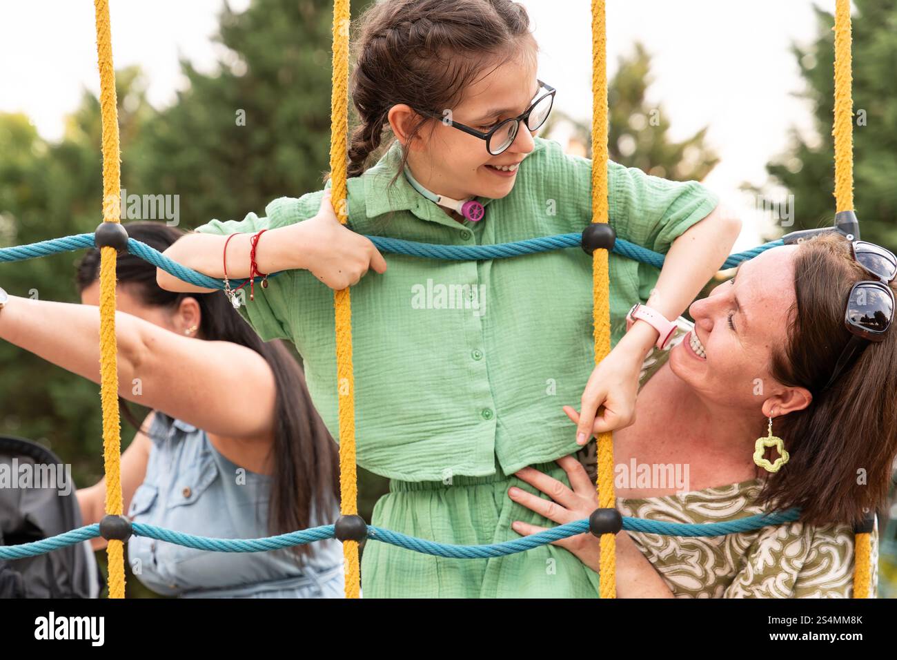 A family enjoys a sunny day at a playground. The focus is on a smiling ...