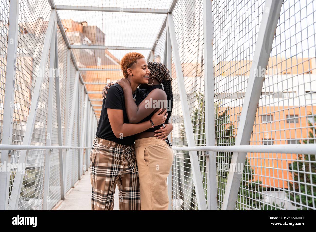 A joyful LGBT multiethnic couple shares a warm embrace on a metal ...