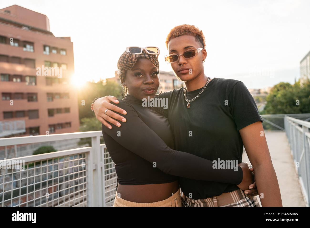 A loving LGBT multiethnic couple embraces outdoors on a bridge during a ...