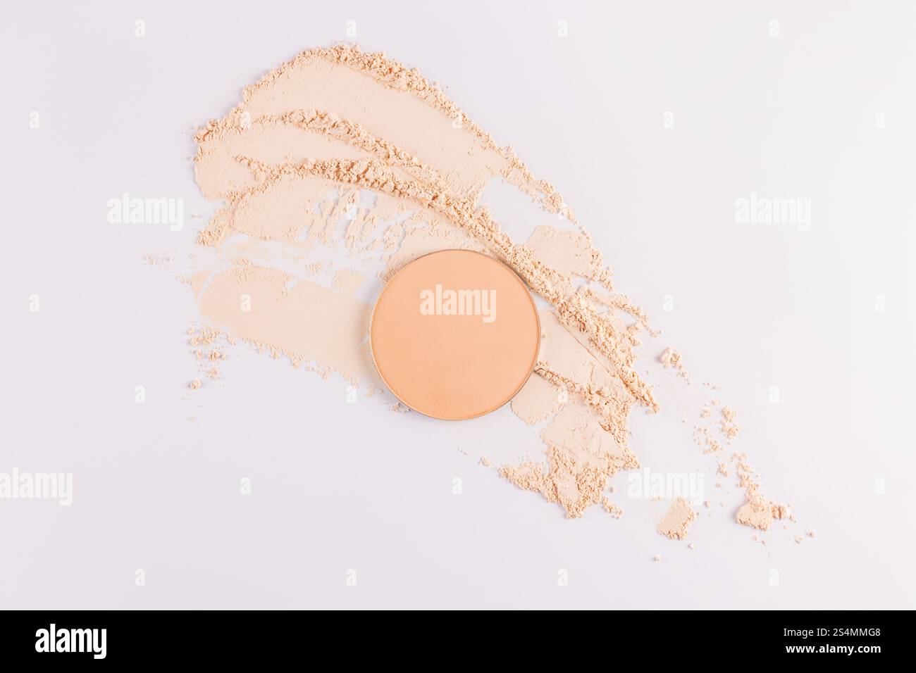 Top view of a circular compact powder alongside scattered loose face ...