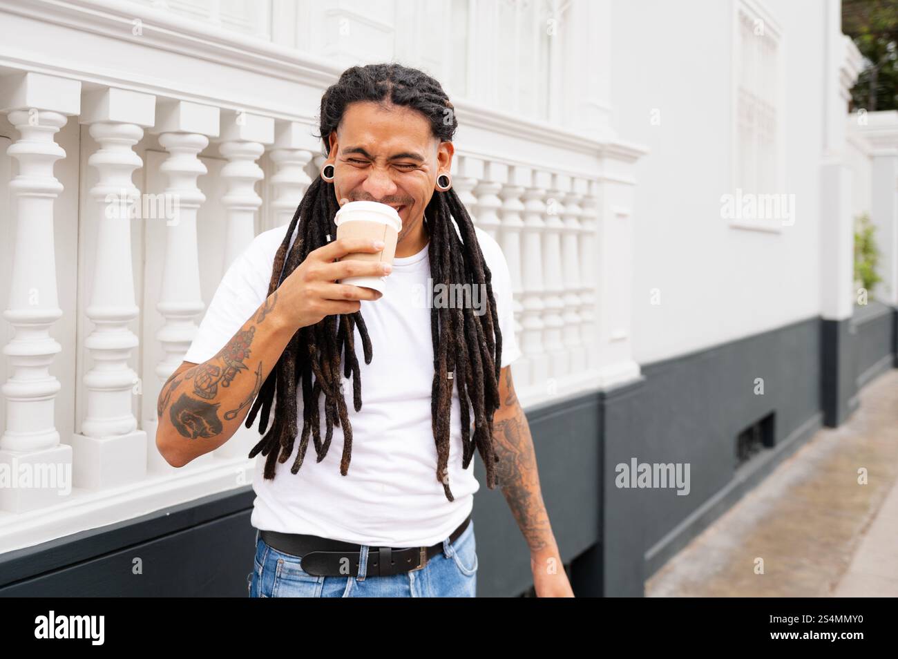 A cheerful man with dreadlocks and tattoos enjoys a coffee in Barranco ...
