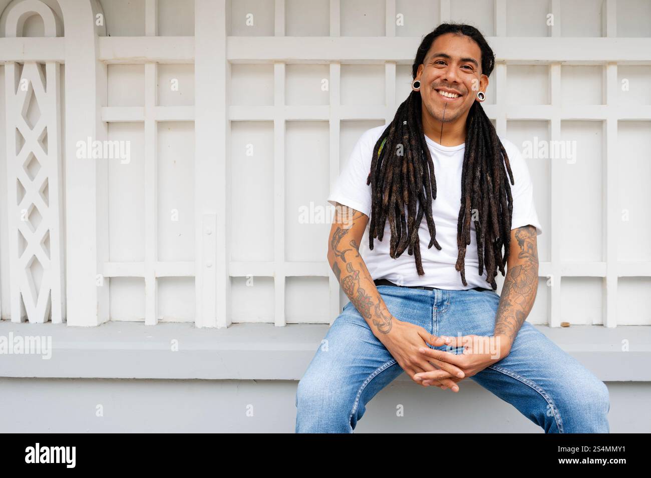 A cheerful man with long dreadlocks and tattoos sits in Barranco, Lima ...