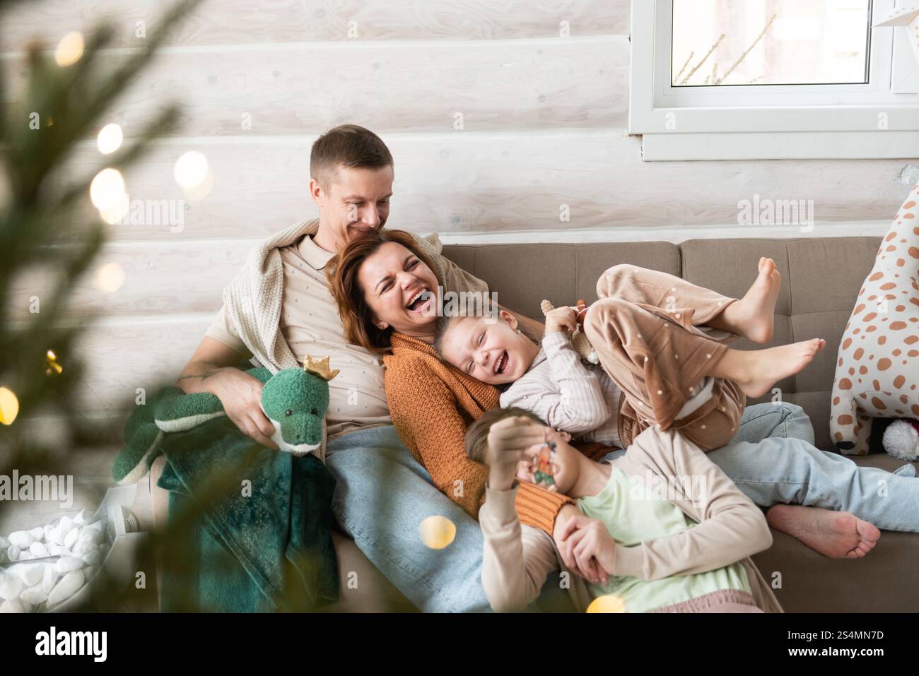 A joyful family celebrates Christmas in a cozy home setting. Two adults ...