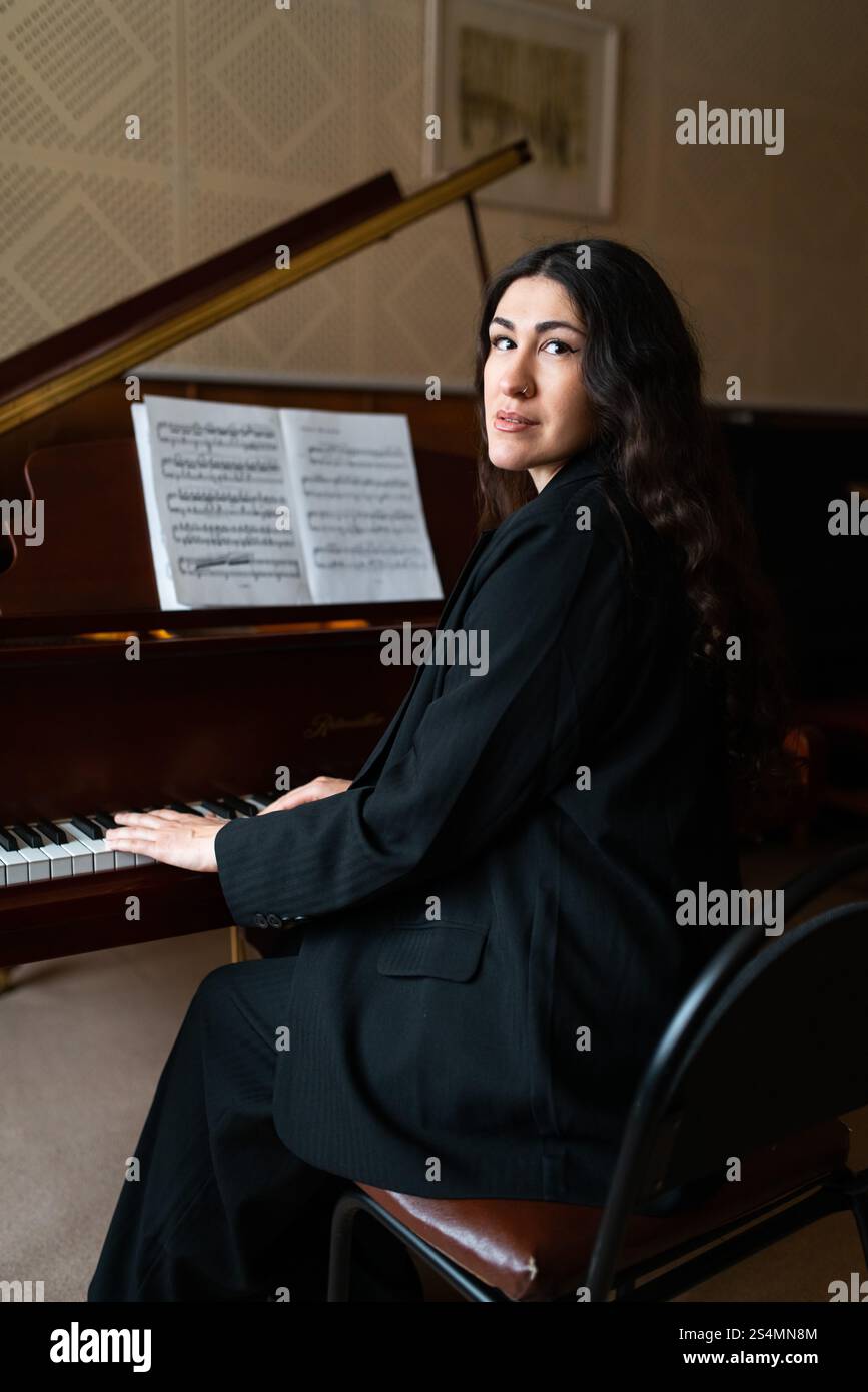 A musician plays sheet music on a grand piano in a cozy studio setting ...