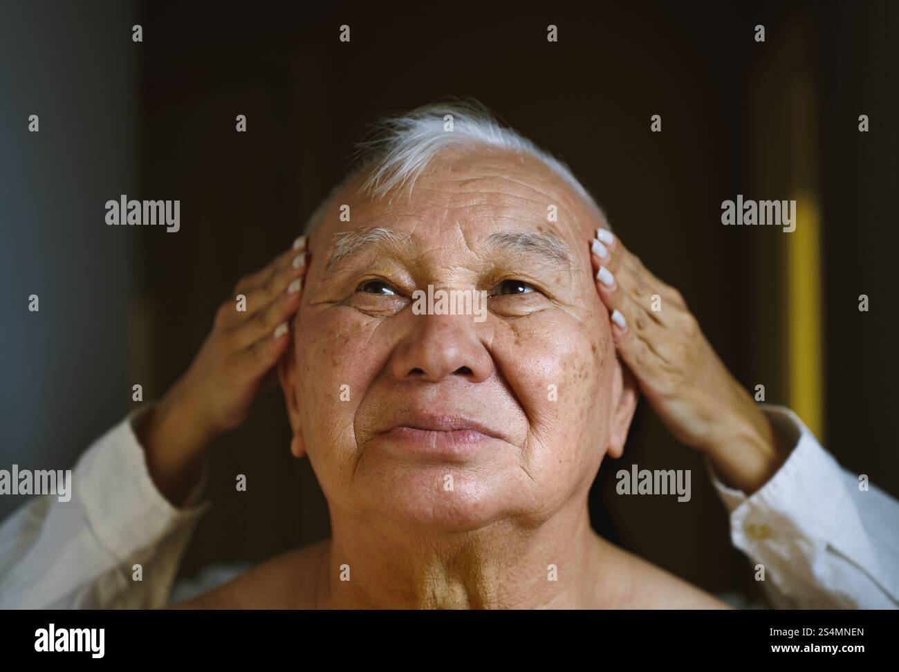 An elderly Asian man enjoys a soothing head massage His serene ...