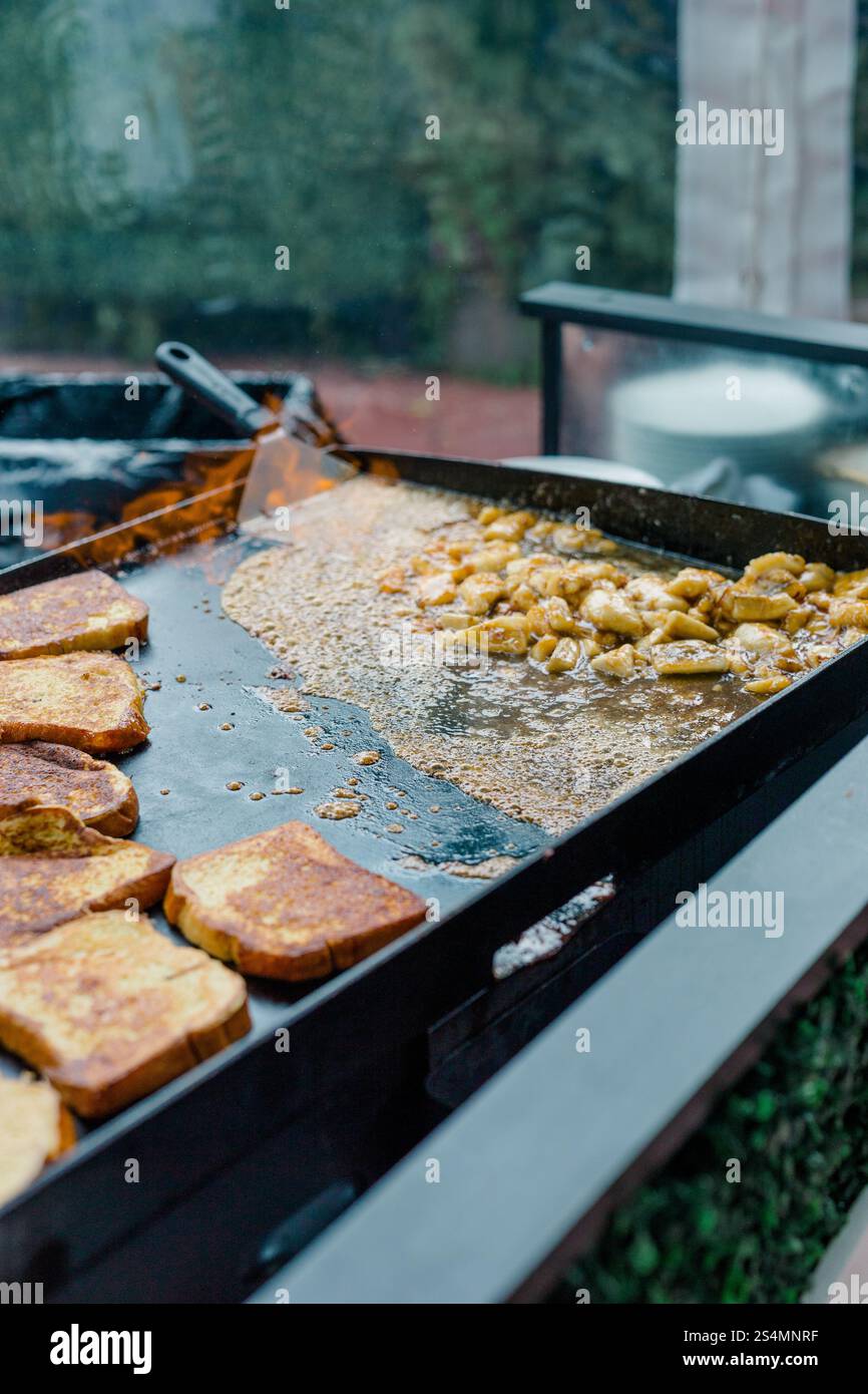 French toast and caramelized bananas cooking on an outdoor griddle ...