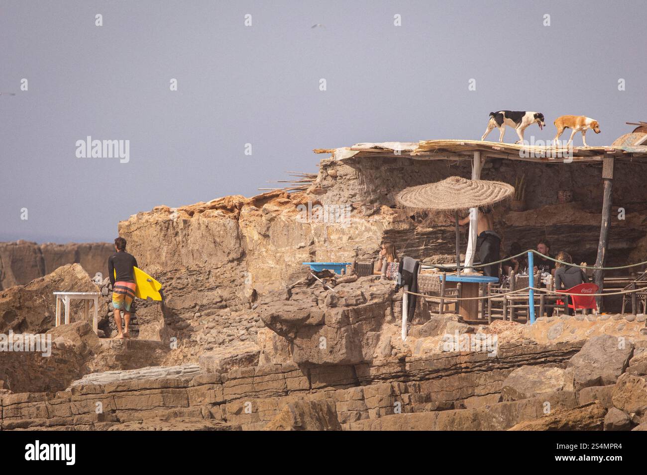 Male Surfer walks with board past rocky Moroccan cliffs Stock Photo - Alamy