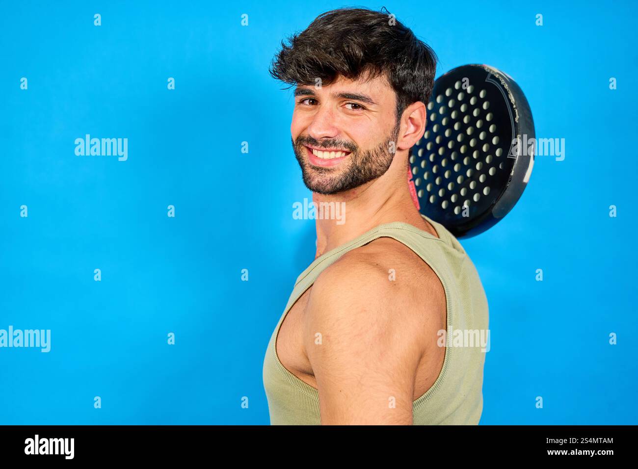 Portrait of a smiling padel player holding a racket on his shoulder ...