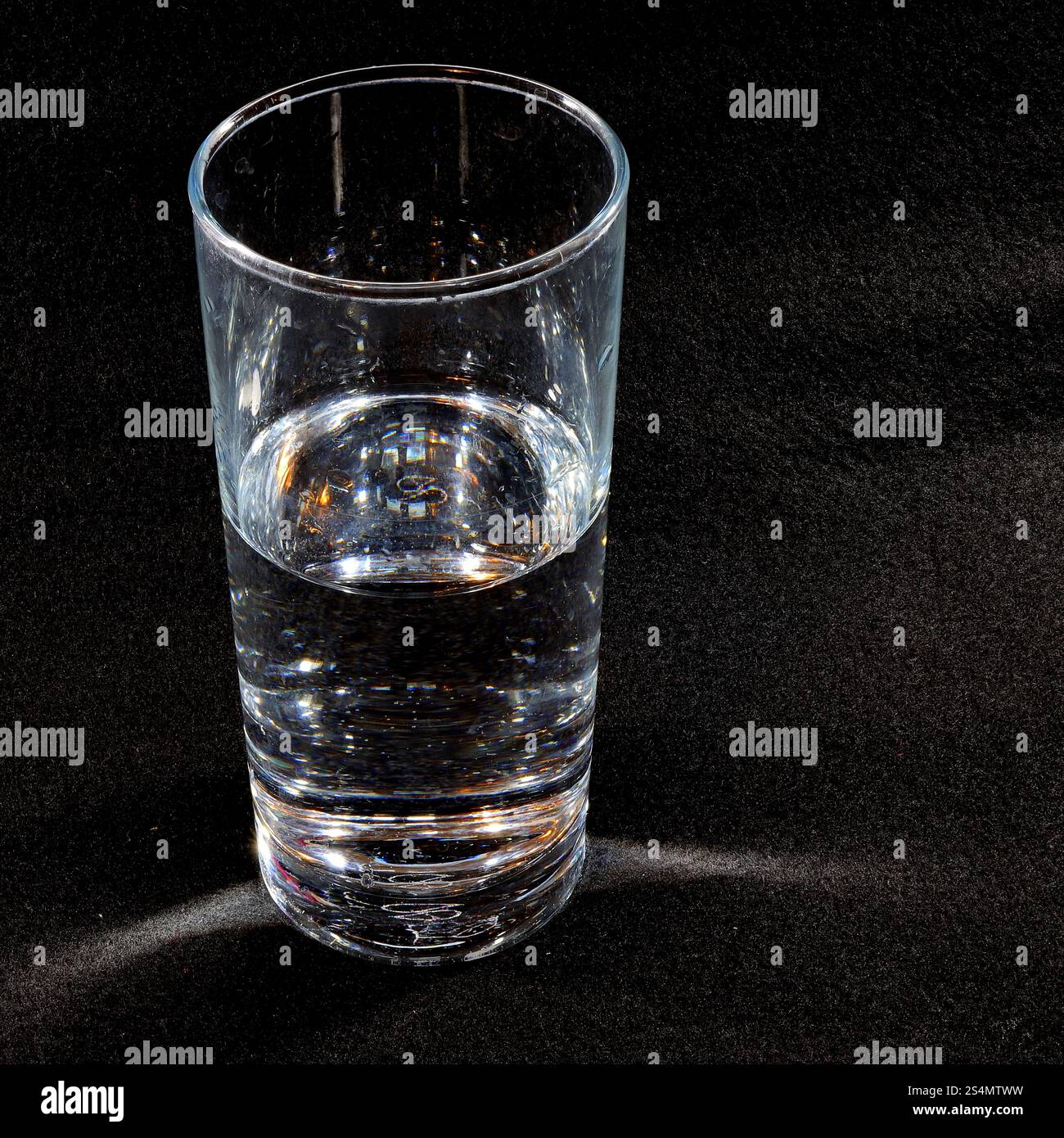 Still life, light and reflections, a glass half filled with water, set ...