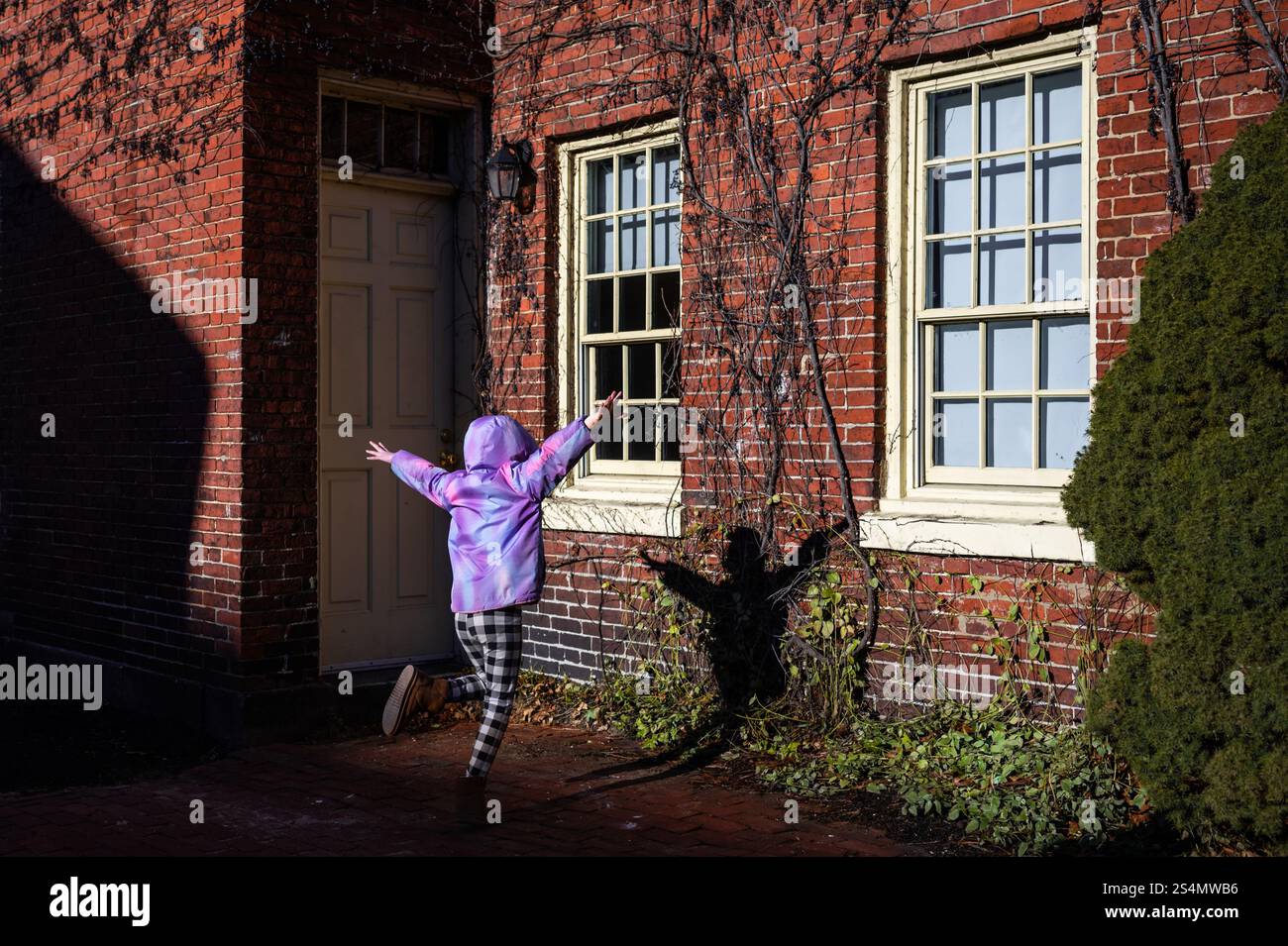 Girl twirling in front of a brick building, casting a playful shadow ...