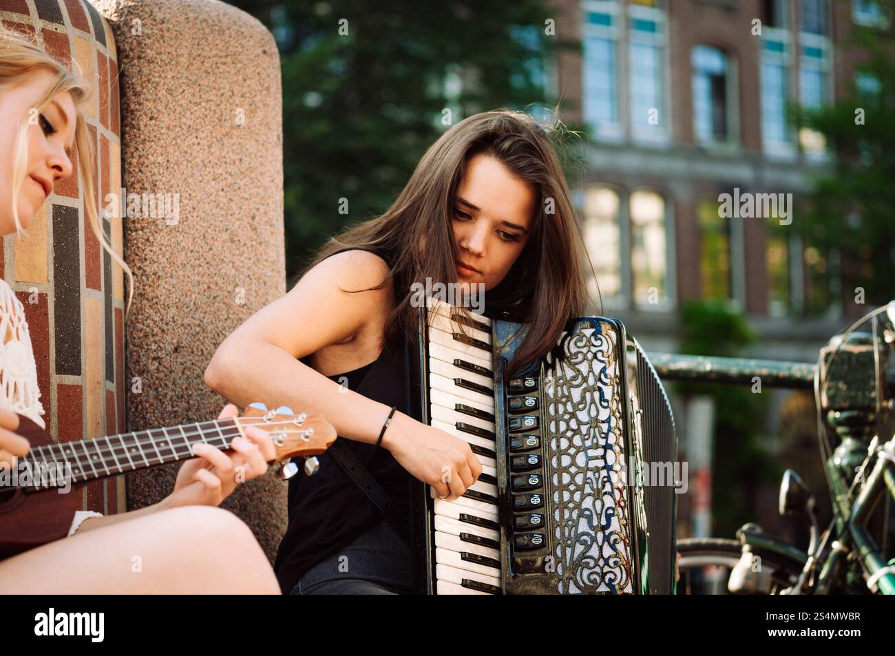 Two women play music on the street, ukulele and accordion, musicians ...