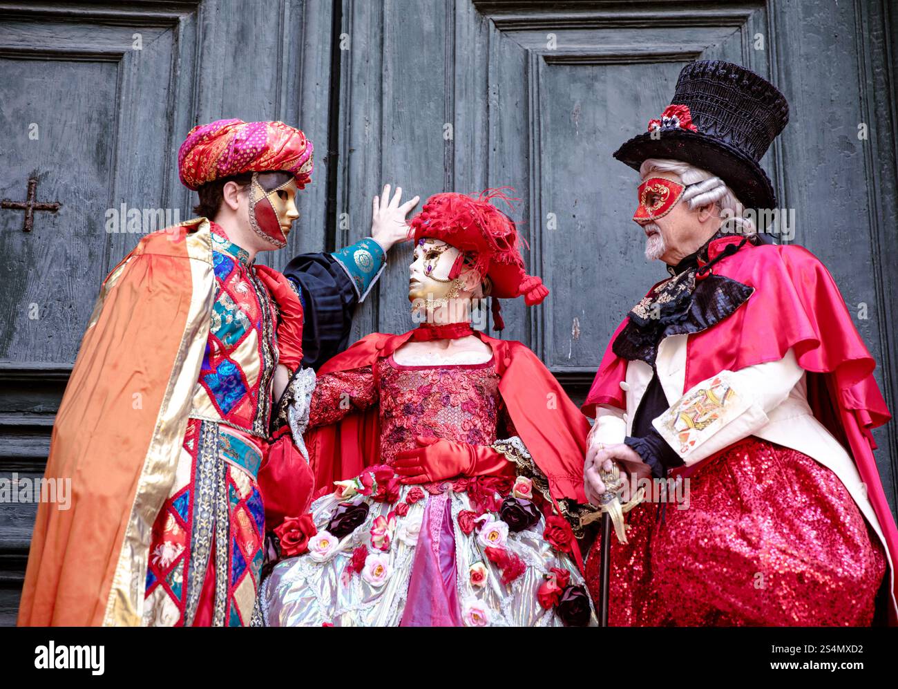 Three adults in colorful venetian masks and costumes standing ne Stock ...