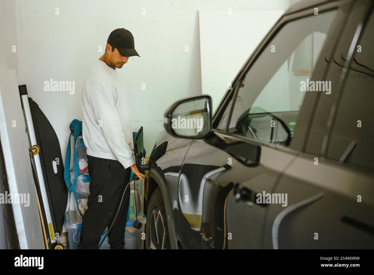Person charging an electric vehicle inside a home garage Stock Photo ...